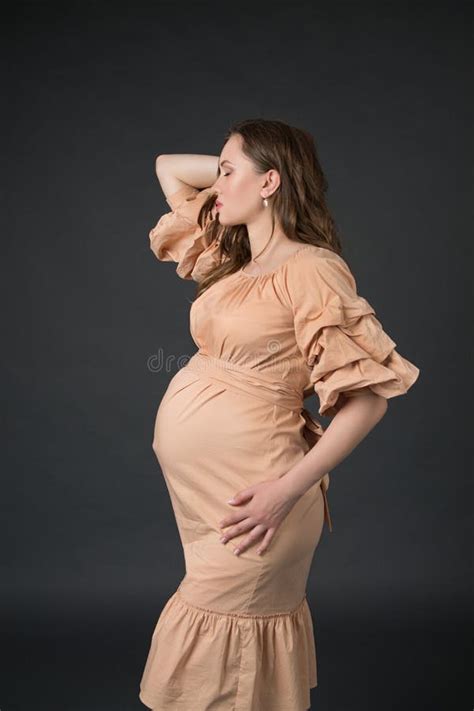 Schwangere Frau In Einem Beige Kleid Das Auf Dem Grauen Hintergrund