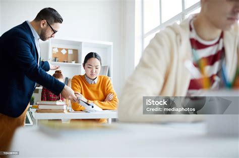 책상에 서 있는 자 켓에서 심각한 엄격한 젊은 수염 교사는 대학에서 수업 중에 학생에 게 실수를 가리키는 교사 교육 관련 직업에 대한 스톡 사진 및 기타 이미지 Istock