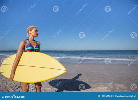 Beautiful Woman In Bikini Standing With Surfboard On Beach In The