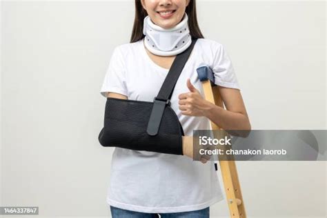 젊은 아시아 여자는 고립 된 팔과 다리를 부러 뜨렸다 여자는 지팡이 목발로 석고 캐스트 부목을 착용했습니다 목 칼라가 있는 슬링 지지 팔을 착용한 환자 생명 보험 및 사고