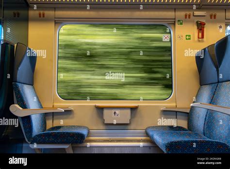 The Interior Of A Passenger Train With A View Of Passing Trees Outside