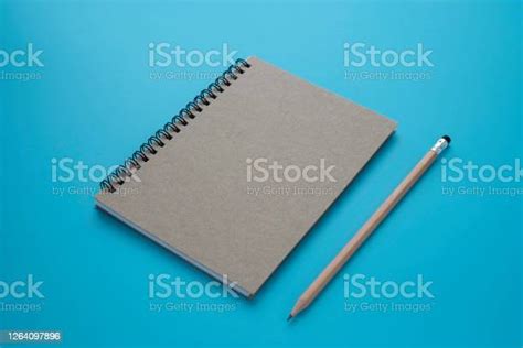 모형을 디자인하기 위해 파란색 배경에 분리 된 갈색 나선형 노트북과 연필위의 상단 보기 교육 및 비즈니스 개념 클리핑 경로가있는