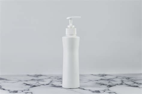 대리석 테이블에 흰색 배경에 빈 빈 모이스처 라이저 용기 크림이나 로션의 화장품 플라스틱 병 라벨없이 비어 있습니다 0명에 대한