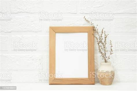 나무 테이블에 프레임 모형 마른 잔디와 현대 세라믹 꽃병 중립 색상 사진 프레임 질감이있는 흰색 벽 배경에 포스터 템플릿