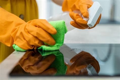 Manos Femeninas En Guantes Limpiando La Superficie De La Cocina Negra