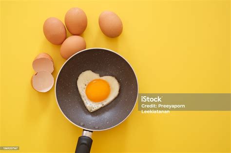노란 배경에 달걀 껍질과 닭고기 계란을 곁들인 팬에 심장 모양의 계란이 튀겨짐 맨 위 보기입니다 건강한 식품 개념 텍스트 공간