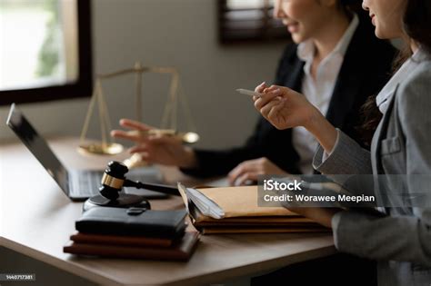비즈니스 여성과 변호사가 사무실의 나무 책상에 황동 스케일로 계약 서류를 논의합니다 법률 법률 서비스 조언 사법 개념 법에 대한