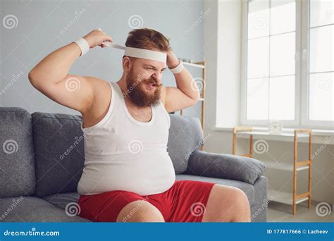 Funny Fat Angry Man In Sportswear Is Sitting On The Sofa In The Room