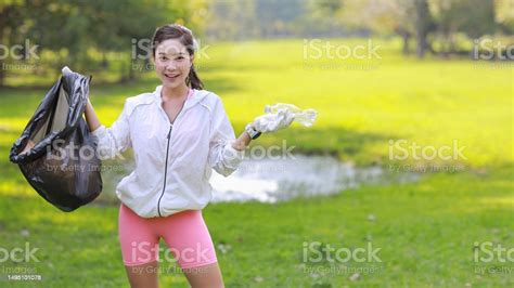 아침 달리기 후 젊은 아름다운 아시아 자원 봉사 여성은 쓰레기 봉투를 들고 공원 잔디밭에서 쓰레기를 줍고 자원 봉사 환경 청소