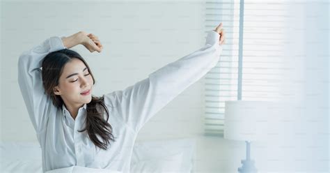 잠옷을 입은 아시아 아름다운 소녀는 아침에 행복으로 일어난다 매력적인 젊은 여성은 웃고 행복하고 긴장을 풀고 집 침실의