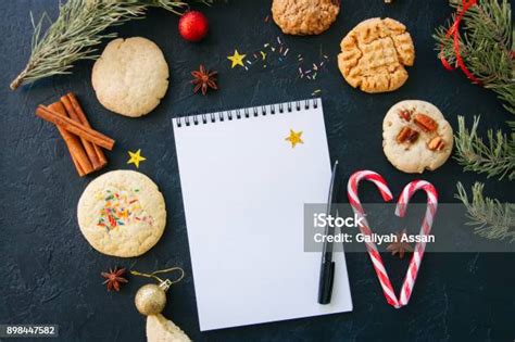 축제 크리스마스 배경입니다 산타 사탕 지팡이 전나무 나무 가지 공 및 검은 돌 배경에서 메모장의 빈 흰색 페이지에 대 한 쿠키의