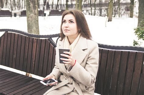Gadis Duduk Di Bangku Taman Memegang Kopi Dan Telepon Di Tangannya