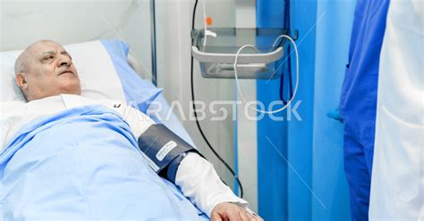 رجل كبير بالسن عربي خليجي سعودي مريض مستلقي على سرير المستشفى، تلقى