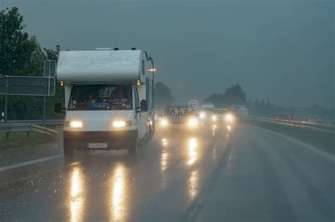 Cars With Low Beams On Drive Along A Motorway In The Rain In The