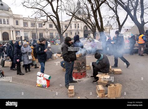 People Warm Up By The Fire Burning In An Iron Barrel Outside The Main Railway Station In Lviv
