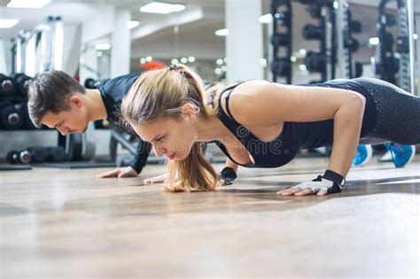 Sporty Young Woman And Man Doing Push Ups Together In Gym Stock Image