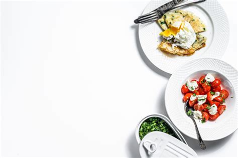 시금치와 계란으로 채워진 팬케이크 접시 체리 토마토와 모짜렐라를 곁들인 카프리즈 샐러드 흰색 배경입니다 맨 위 보기 복사 공간