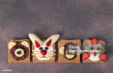 갈색 배경에 딸기 바나나 크림 치즈 초콜릿 코코넛 플레이크가 있는 병아리 곰 토끼 원숭이 모양의 아이들을 위한 4개의 달콤한 토스트 0명에 대한 스톡 사진 및 기타 이미지