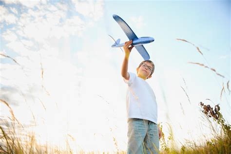 O garoto corre um avião de brinquedo filho sonha em voar menino feliz corre no sol brincando