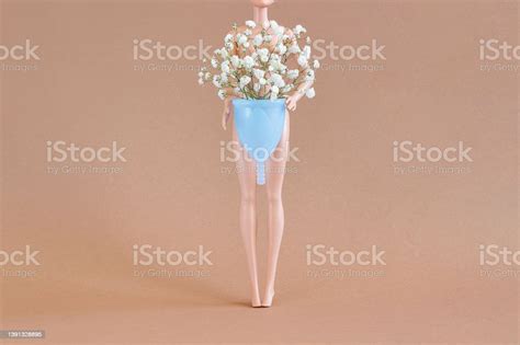 여성 인형은 복사 공간이있는 갈색 배경에 꽃다발이 섬세한 꽃과 함께 파란색 생리컵을 들고 있습니다 여성 친밀한 위생 여성 건강 개념 환경 친화적 인 제로 폐기물 대안 0명에