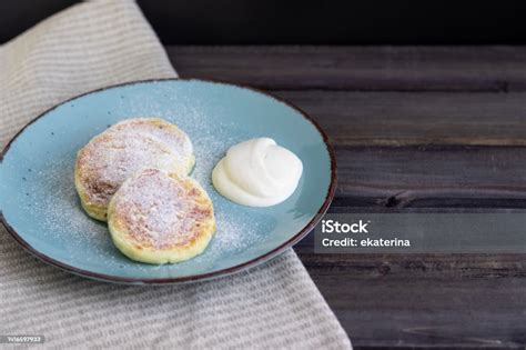 검은 판에 사워 크림과 검은 색 배경에 사워 크림을 곁들인 코티지 치즈가있는 팬케이크 가루 설탕을 뿌린다 시르니키에 대한 스톡