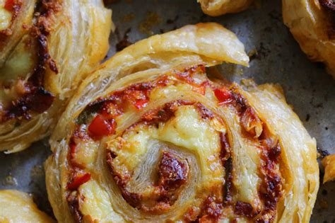 퍼프 페이스트리 피자의 클로즈업 이미지는 양피지 그리스 증거 종이 줄 지어 베이킹 트레이 체다 치즈와 토마토로 채워진 퍼프 페이스트리 황금 계란 세척과 갓 구운 높은 전망에