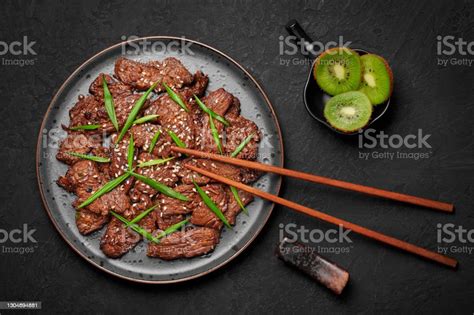 어두운 슬레이트 테이블 상단에 검은 접시에 쇠고기 불고기 불고기 소스와 키위가 있는 한국 요리 고기 요리 전통 아시아 음식 위쪽