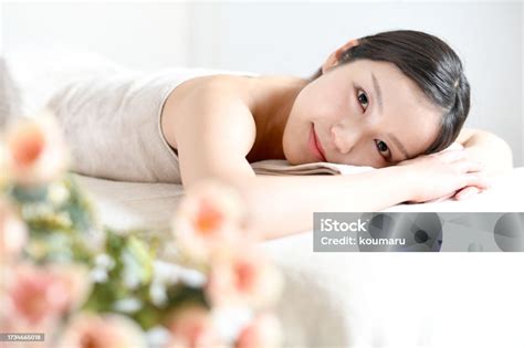 A Young Asian Woman Lying Face Down Receiving Massage Treatment In Bed