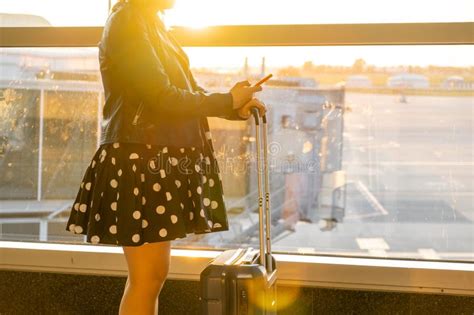 A Woman Is Checking The Departure Time At The Airport In Sunlight Stock