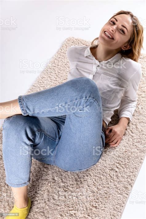 흰색 셔츠와 청바지에 젊은 행복 미소 소녀는 흰색 배경에 양탄자에 바닥에 누워 20 29세에 대한 스톡 사진 및 기타 이미지