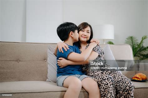 귀여운 아기와 함께 재미있는 엄마 거실에서 함께 노는 어머니 엄마가 소파에 앉아 있는 동안 뒤에 서서 엄마를 껴안고 있는 아시아