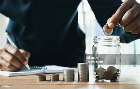 남자는 돈을 절약하고 책상에 유리 항아리에 동전을 넣어에 대한 성도 문서입니다 손에 대한 스톡 사진 및 기타 이미지 손