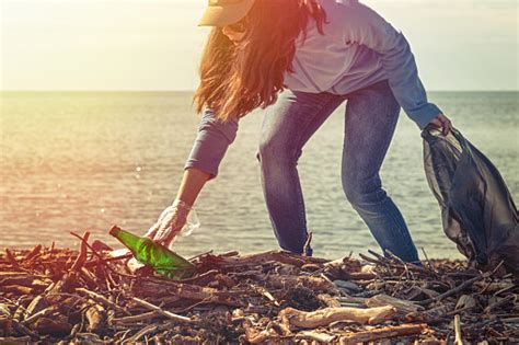 여성 자원 봉사자는 쓰레기의 해변을 청소하는 데 도움이됩니다 지구의 날과 환경 개선 개념 미래 세대 개념을 위한 생태와 안전 왼쪽 모서리에서 비추는 라이트 가방에 대한 스톡