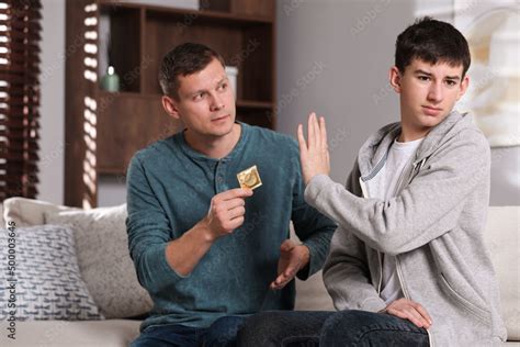 Father Talking With His Teenage Son About Contraception At Home Sex Education Concept Stock