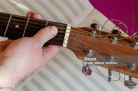 한 남자의 손에는 보라색 배경의 열린 음악 노트북 위에 어쿠스틱 기타를 들고 있다 갈색에 대한 스톡 사진 및 기타 이미지 갈색 기술 기타 현악기 Istock