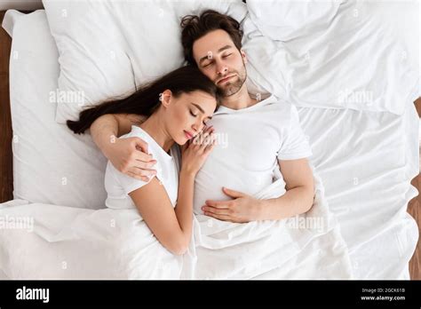 Married Couple Sleeping Embracing In Comfortable Bed Indoor Top View