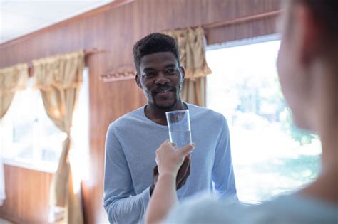 백인 여성이 남편에게 물 한 잔을 가져다 주며 인후통으로 고통받는 아프로 미국 남자 2명에 대한 스톡 사진 및 기타 이미지 2명 가정 생활 감압 우물 Istock