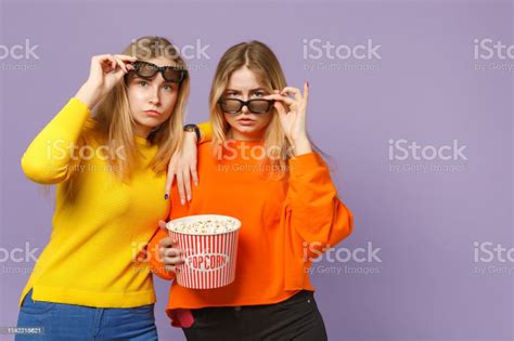 두 여자는 3d 아이맥스 안경 파스텔 바이올렛 블루 벽 배경에 고립 된 팝콘을 보고 영화 필름에 젊은 금발 쌍둥이 자매 소녀를