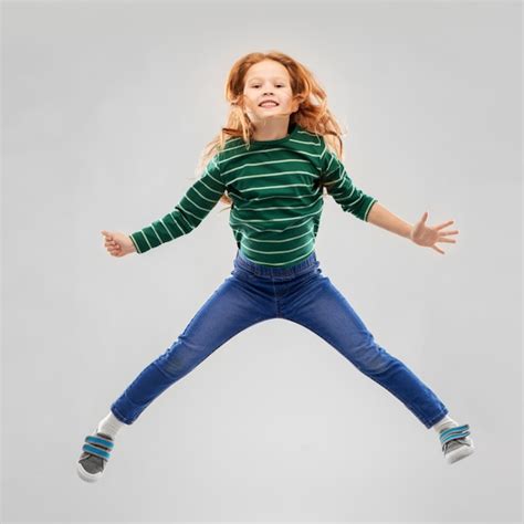 Premium Photo Smiling Red Haired Girl In Striped Shirt Jumping