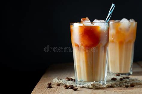 Ice Coffee In A Tall Glass With Cream Poured Over Ice Cubes And Beans