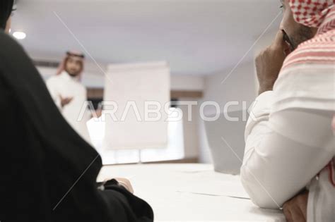 مدرب عربي سعودي يقوم بالشرح لمتدربين سعوديين خليجيين على سبورة بيضاء