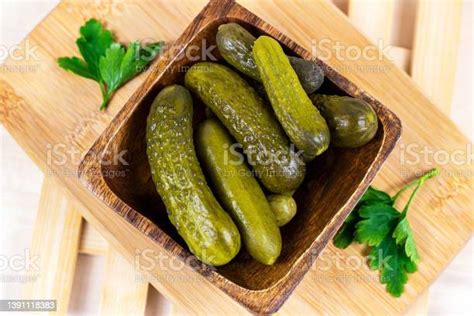 부엌의 라이트 커팅 보드 배경에 나무 그릇에 신선한 파슬리와 함께 맛있는 수제 녹색 절인 오이 작은 오이에 대한 스톡 사진 및