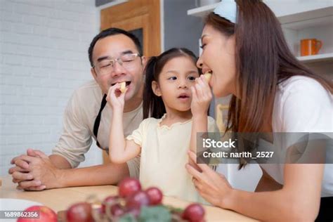 부엌에서 아버지 어머니 딸과 함께 행복한 가족 딸이 집에서 함께 사과 과일을 먹이고 엄마 아빠 아이는 유대감과 관계 생활 방식과