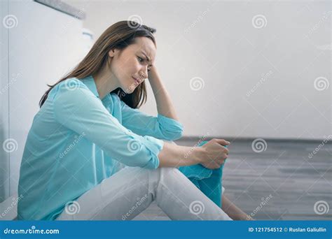 Young Woman Sitting On Kitchen Floor Holding Her Head And Crying Upset