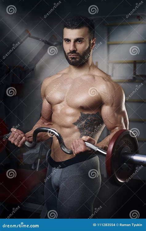 Muscular Topless Man Doing Standing Ez Bar Curls Topless In The Gym