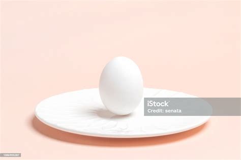파스텔 핑크 를 배경으로 흰 닭 달걀 한 개가 흰 접시에 서 있습니다 부활절 최소한의 이미지 4월에 대한 스톡 사진 및 기타