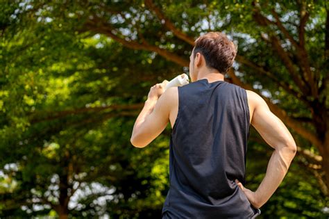 여름날 도시 공원에서 조깅을 한 후 물을 마시는 스포티한 잘생긴 남자 젊은 남자는 건강하고 활동적인 라이프스타일을 위해 자연