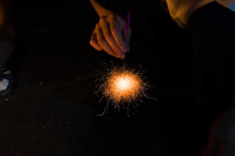 Premium Photo Cropped Hand Of Woman Holding Sparkler Against Sky At Night