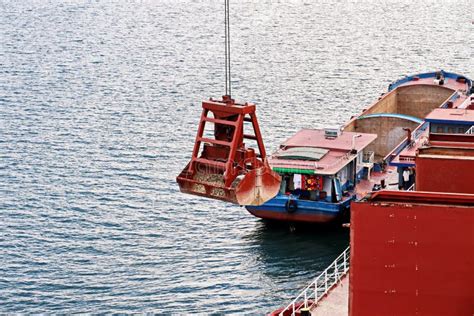Loading Bulk Cargo Of Limestone From Barges Into A Bulk Carrier By Using Ship Cranes And Grabs