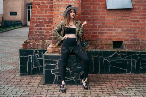 A Slender Girl With Blond Long Hair In Black Leggings A Tank Top A